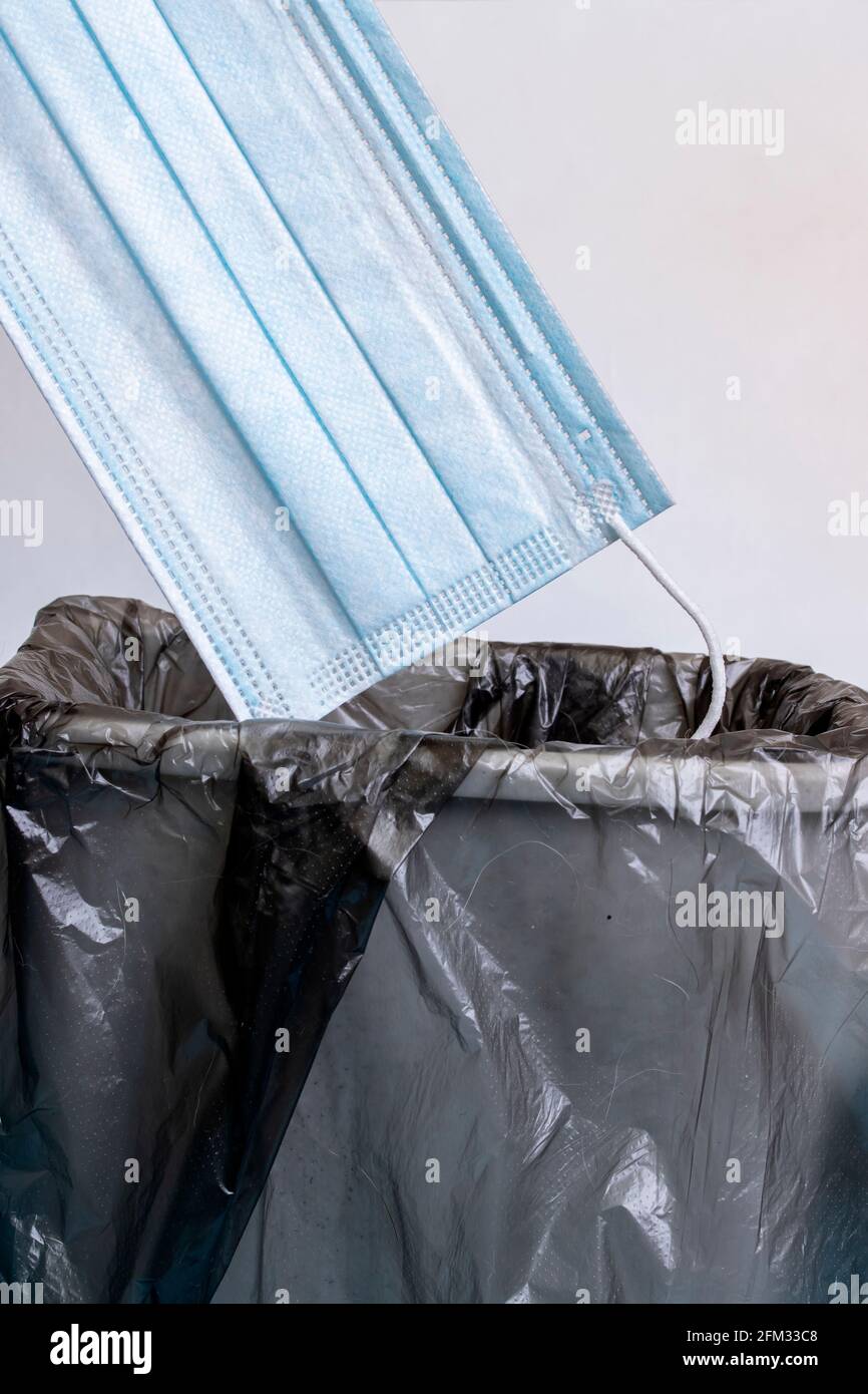 Throwing a medical mask into a trash can Stock Photo - Alamy