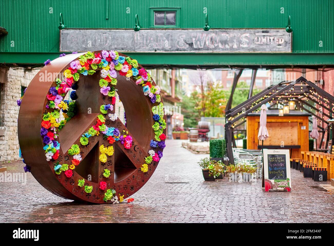A peace sign wheel sculpture with flowers in the trendy side streets of ...