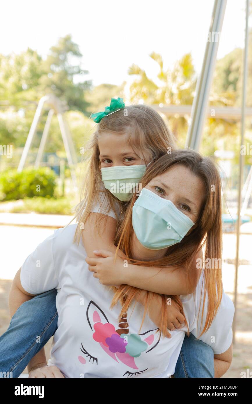Spanish mom with her daughter on her back looking into the camera while ...