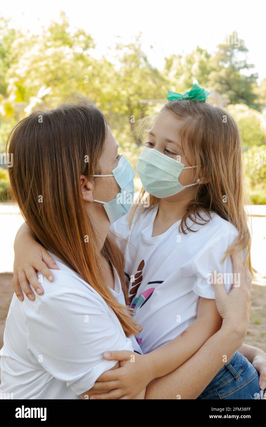Spanish mom holding her young daughter as they look into each other's ...