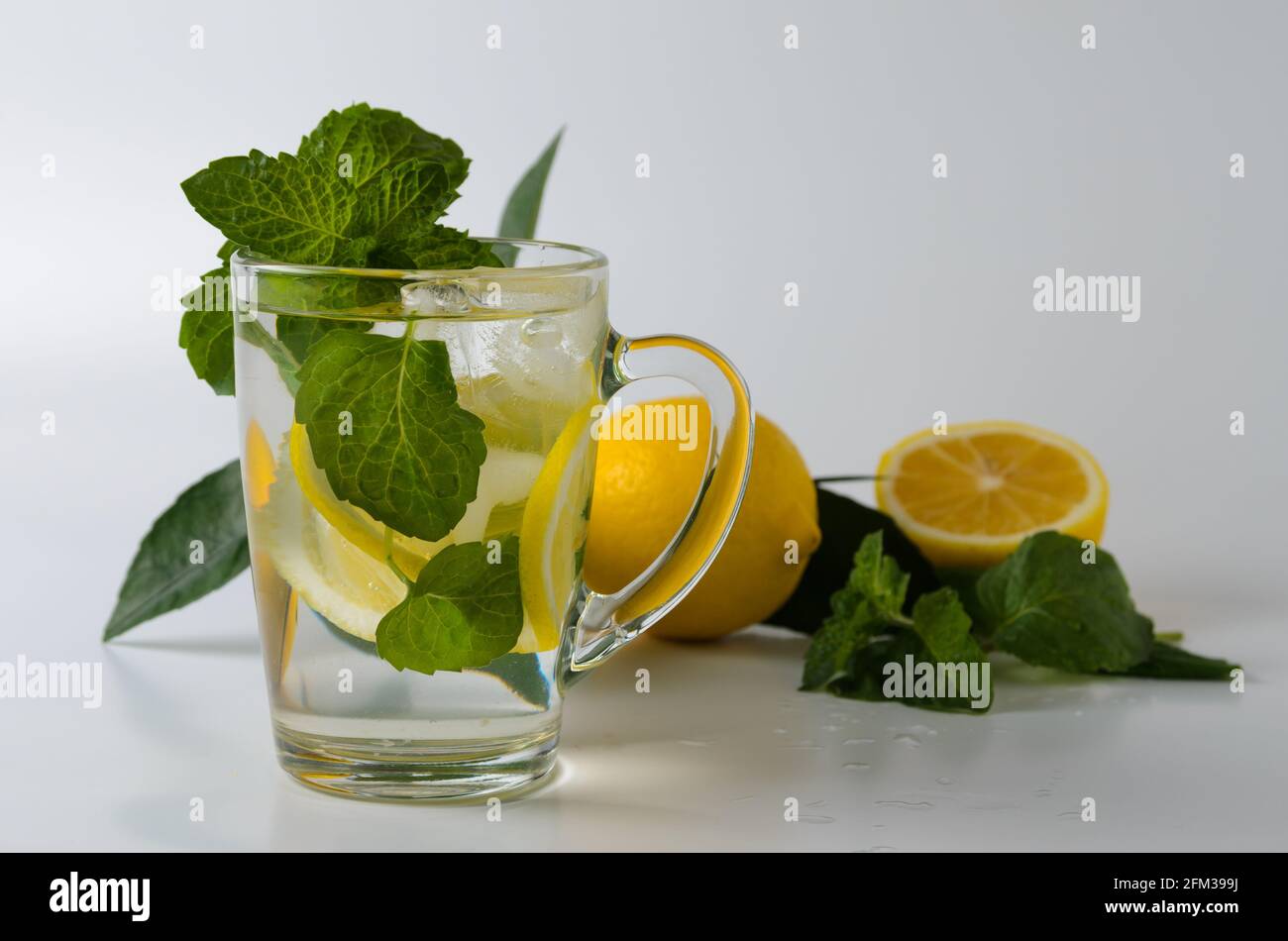 A glass glass of lemonade. Water with lemon slices, mint leaves and ice ...