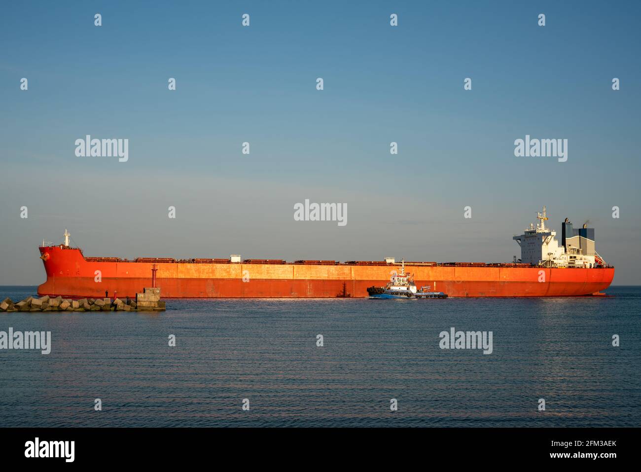 Large ocean-going cargo ship in orange. The dry cargo ship enters the ...