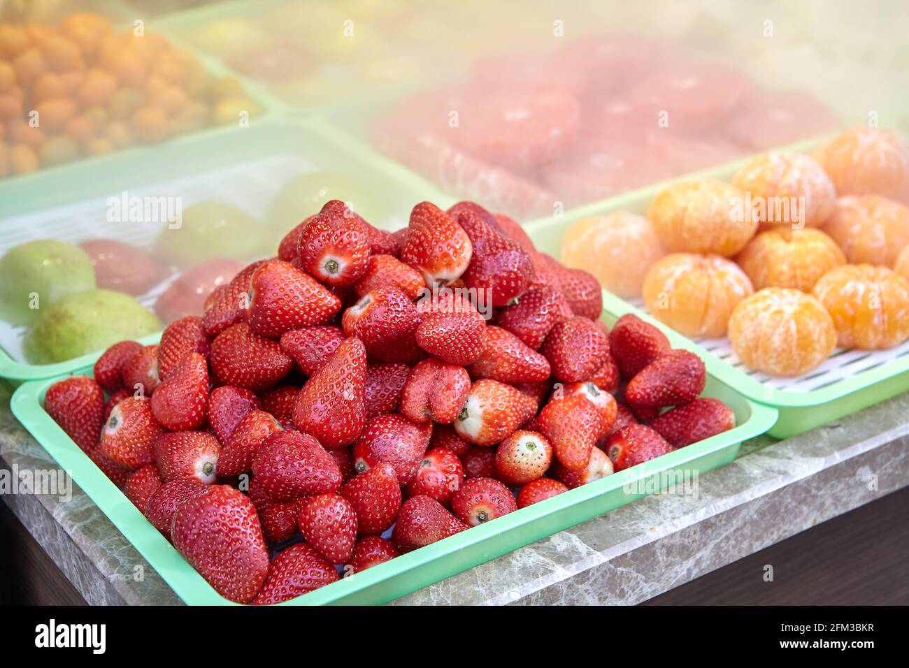 Chilled fruits lie in tray on store counter surrounded by fog Stock ...