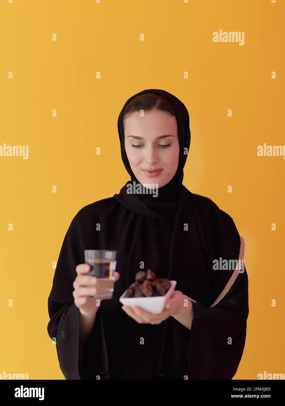 Modern muslim woman in abaya holding a date fruit and glass of water in ...