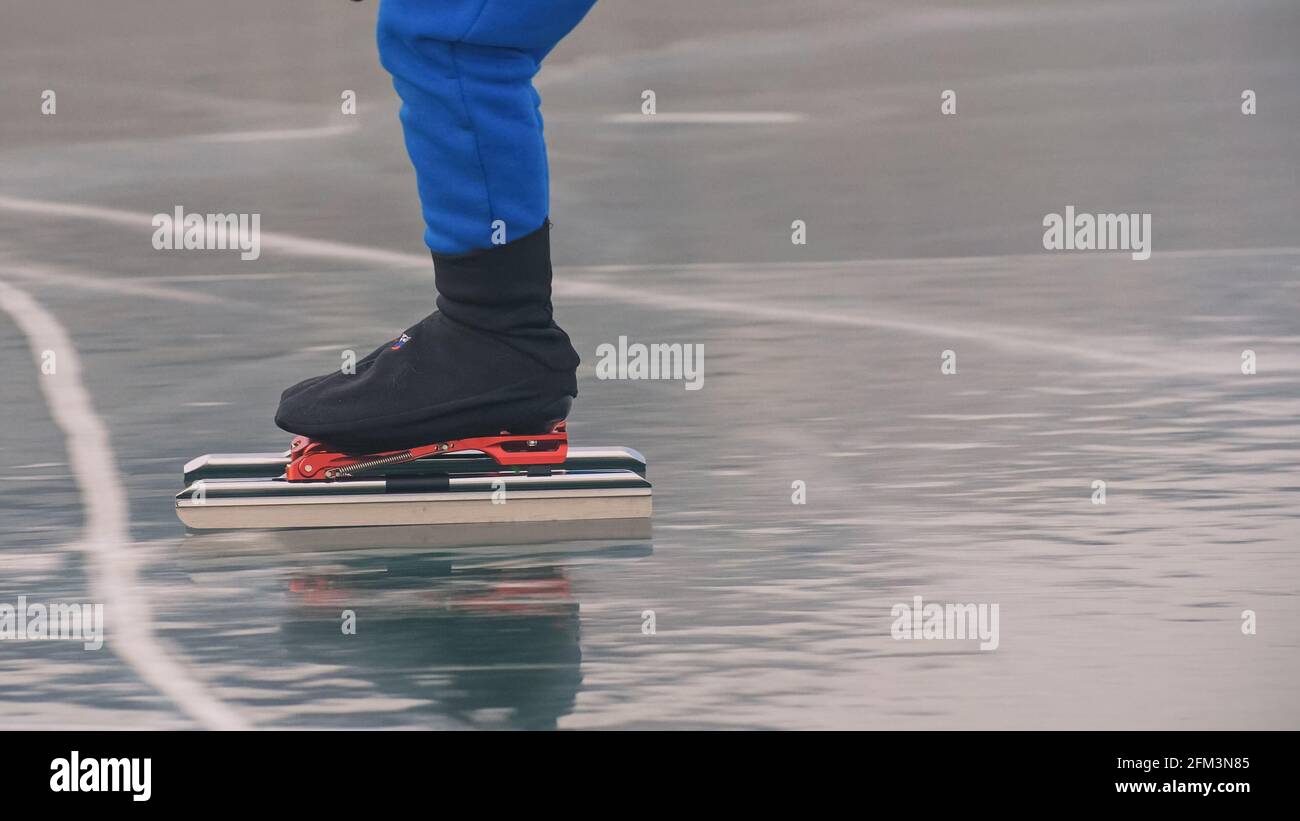 The child train on ice speed skating. The legs in skates close up. The ...