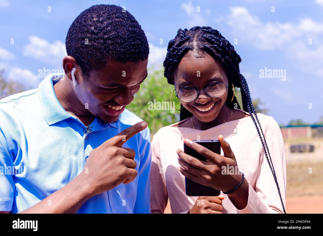 Happy Nigerian couple looking at phone screen and celebrating good news ...