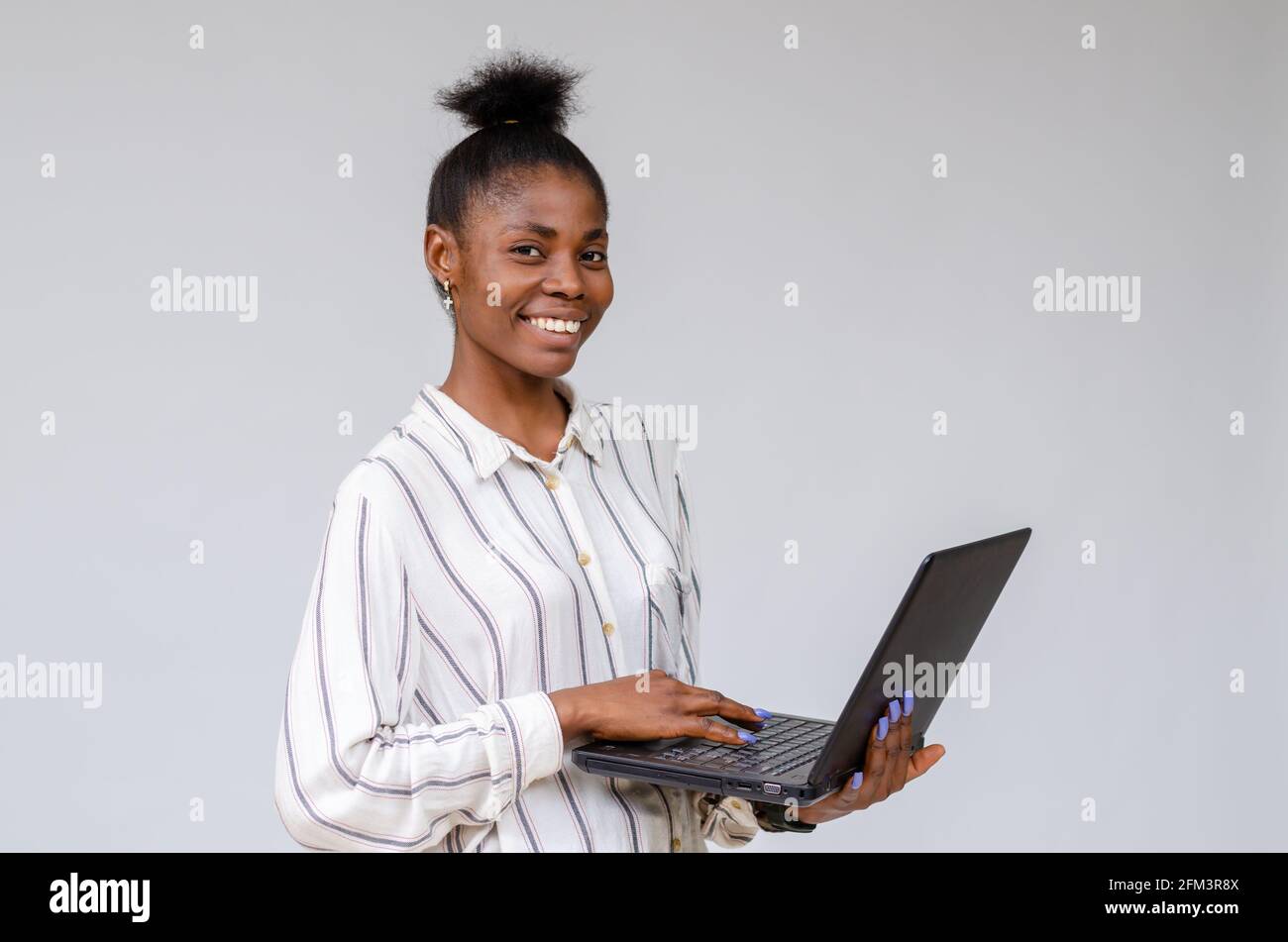 Happy Nigerian woman smiling at the camera after completing her work on ...