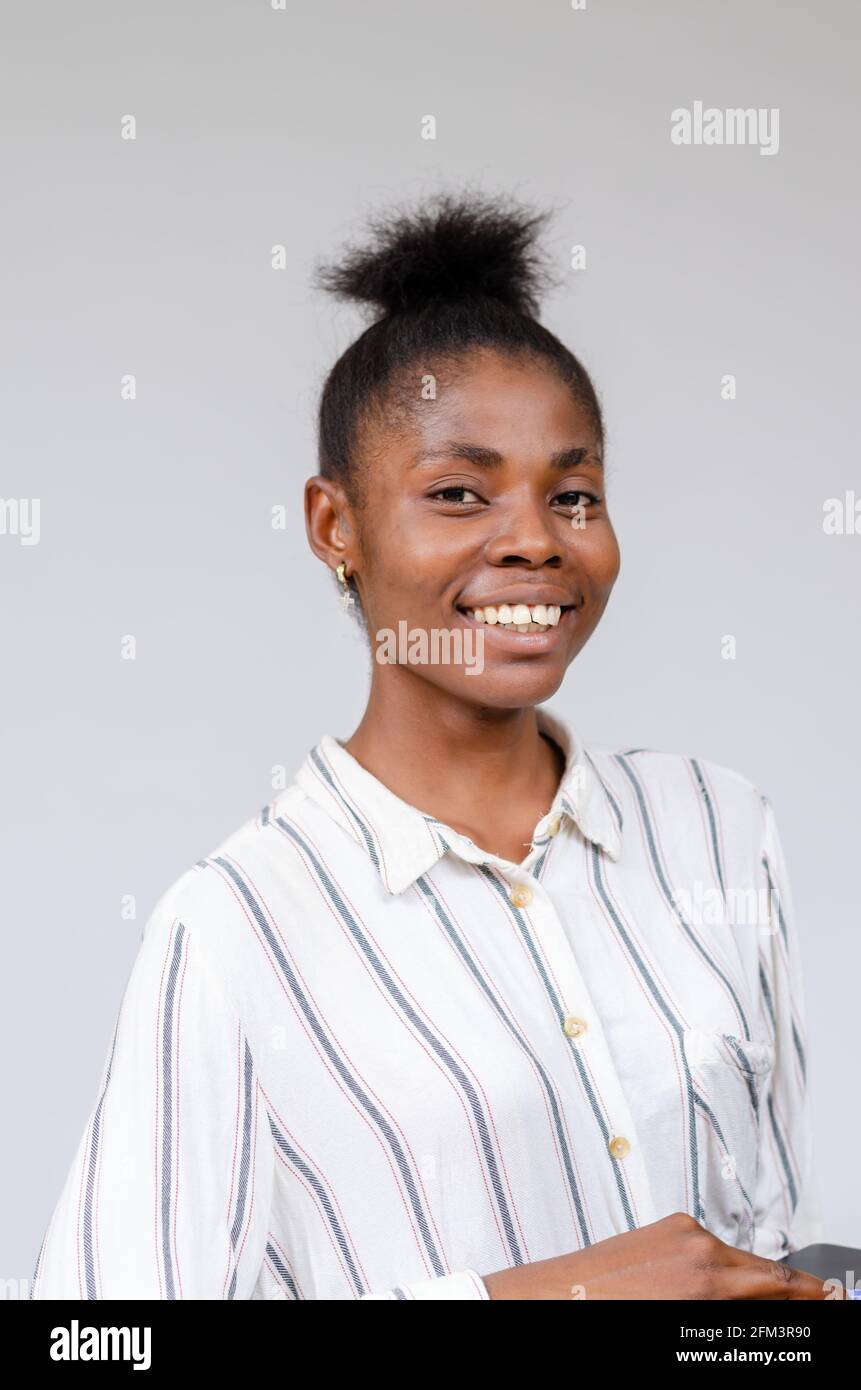 Vertical shot of a young Nigerian employee smiling at the camera after ...