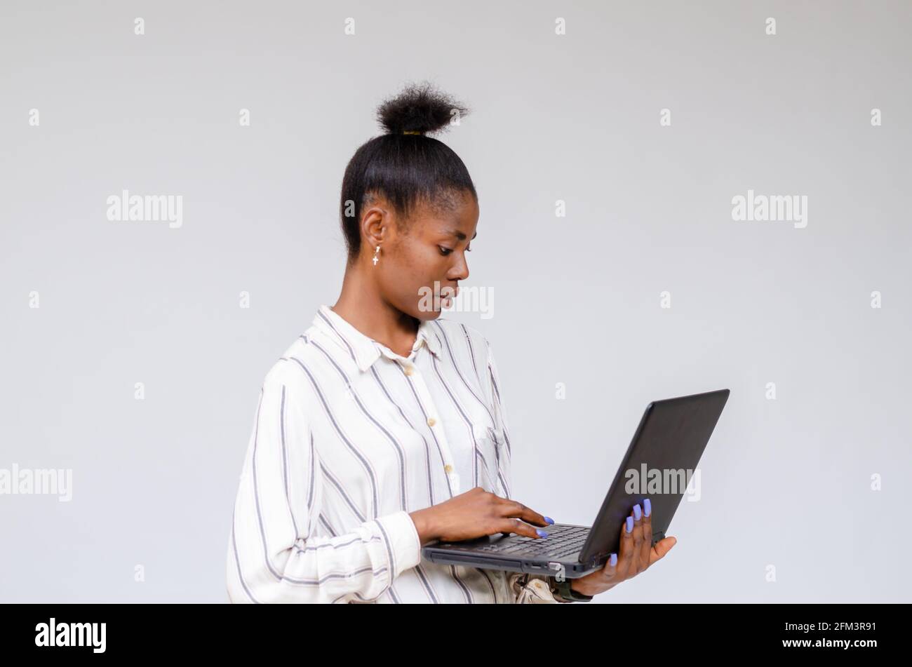 Nigerian woman in the office holding a laptop Stock Photo - Alamy