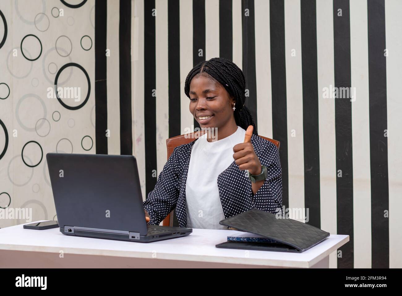 Happy female Nigerian employee in the office as work goes smoothly ...