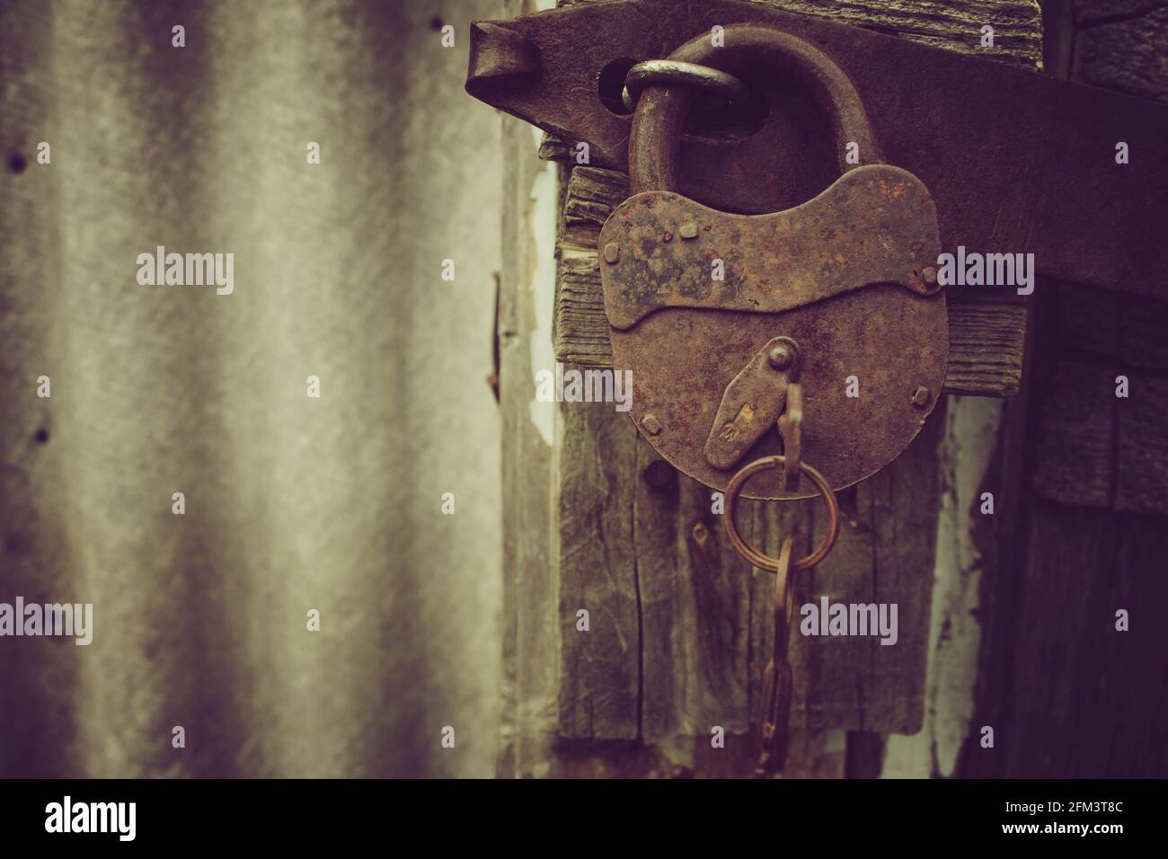 Iron rusty lock with a key. Closed door. Locked gates to the barn lock ...