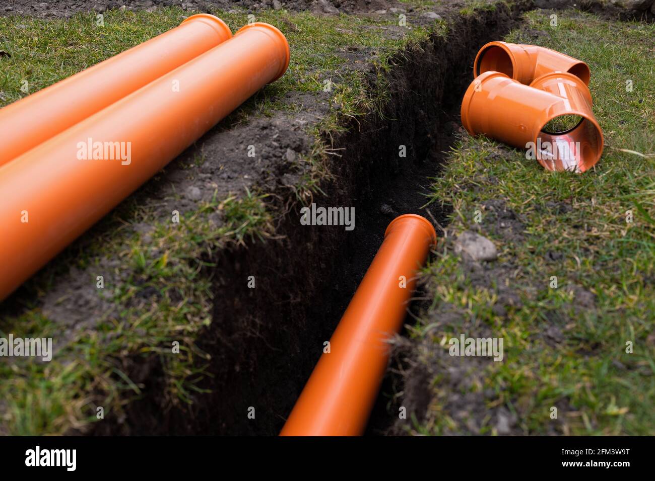 Laying down orange PVC drainage pipes into the ground Stock Photo - Alamy