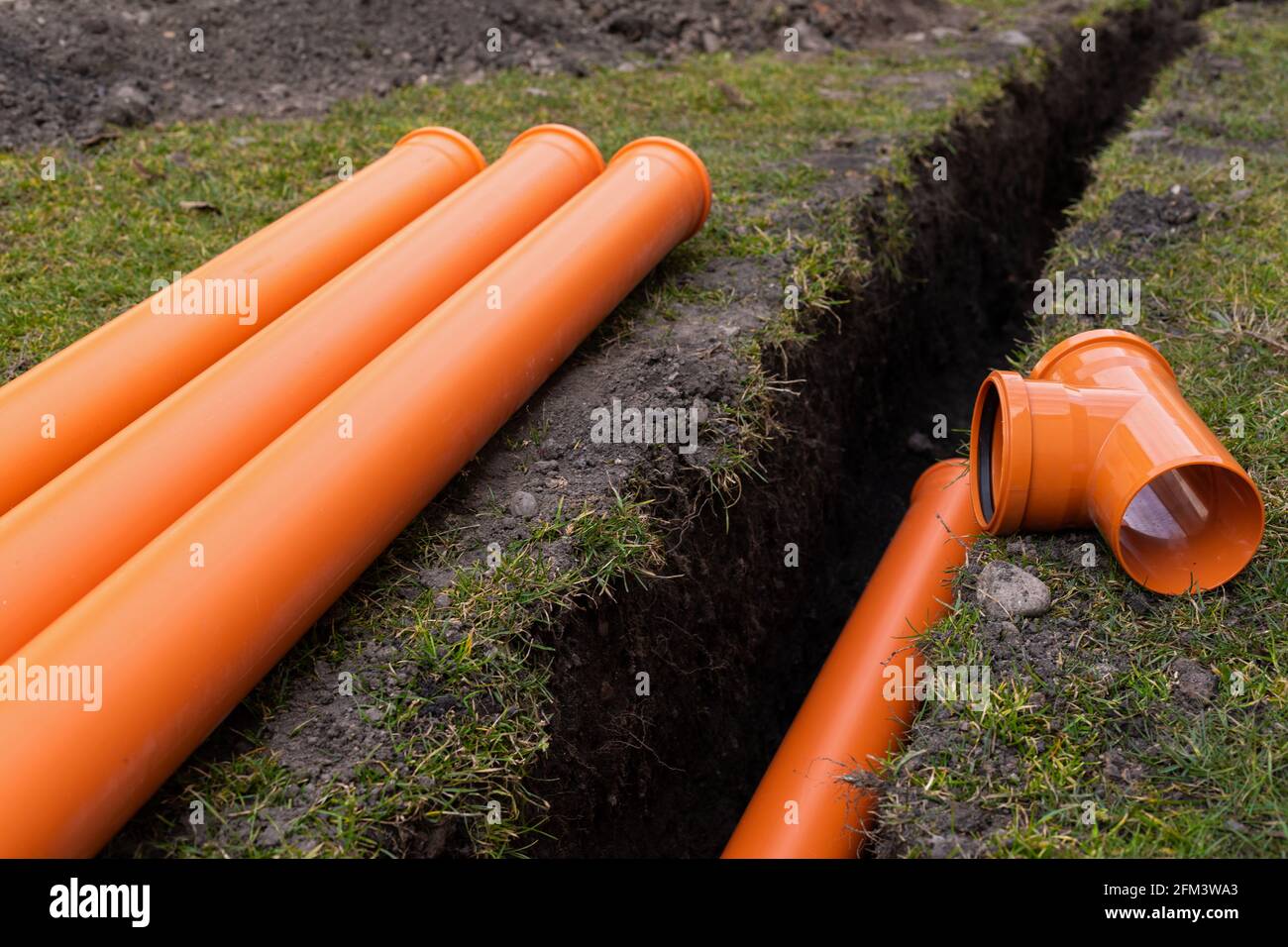 Laying down orange PVC drainage pipes into the ground Stock Photo - Alamy
