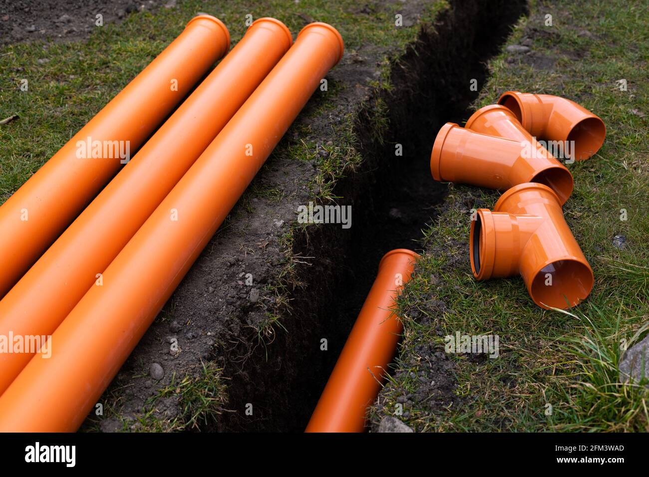 Laying down orange PVC drainage pipes into the ground Stock Photo - Alamy