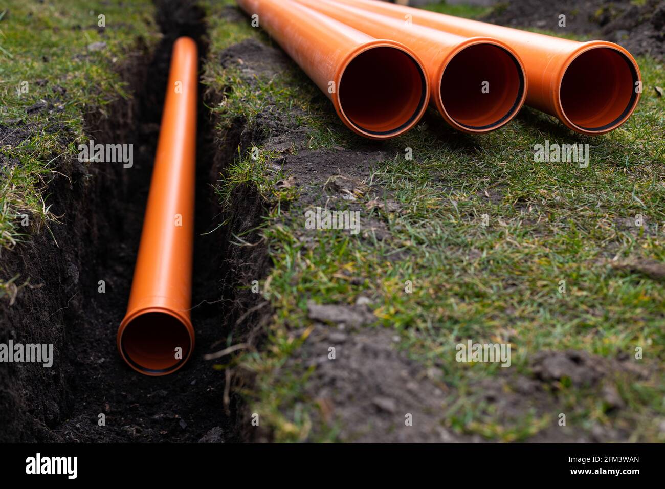 Laying down orange PVC drainage pipes into the ground Stock Photo - Alamy