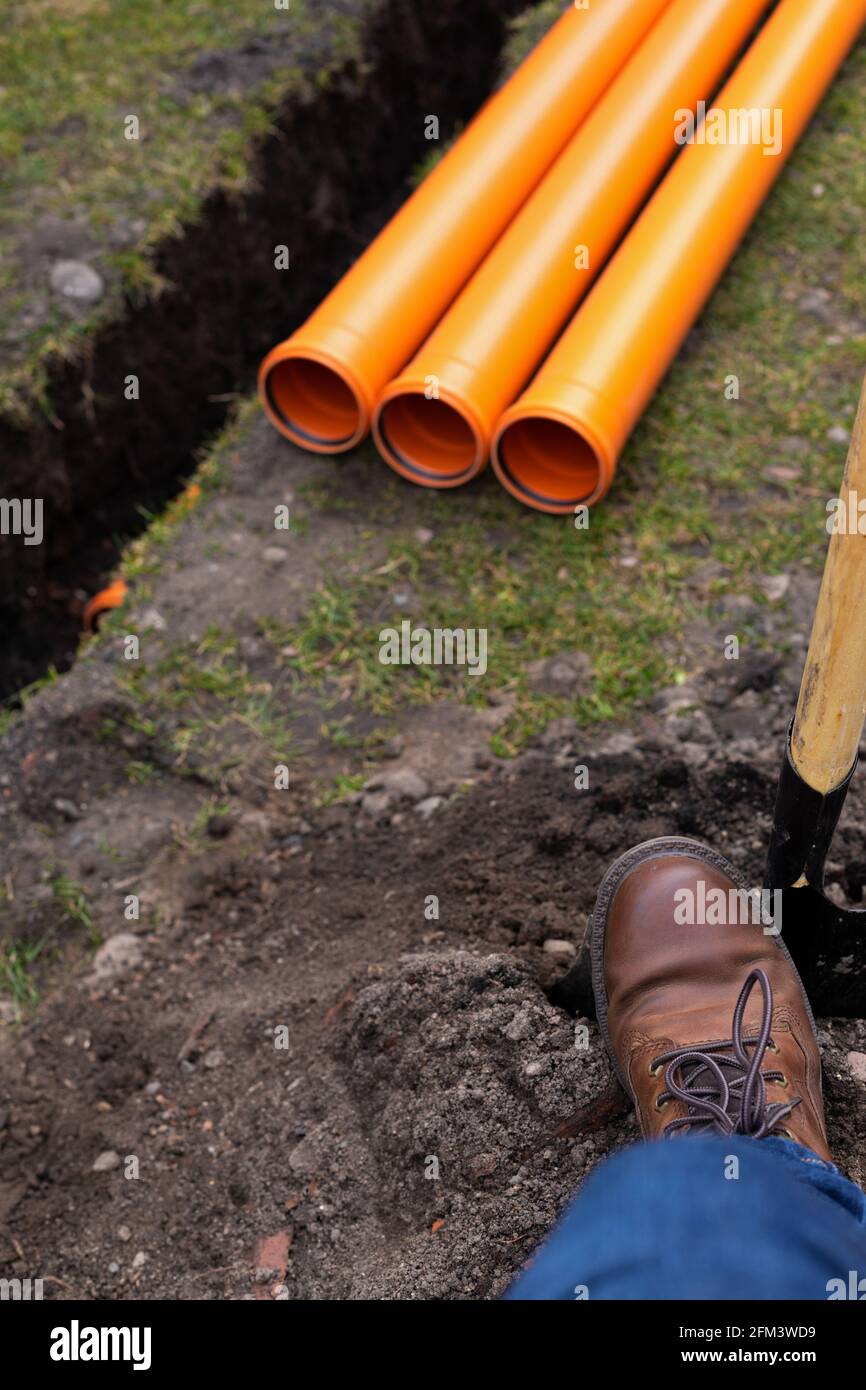 Laying down orange PVC drainage pipes into the ground Stock Photo - Alamy