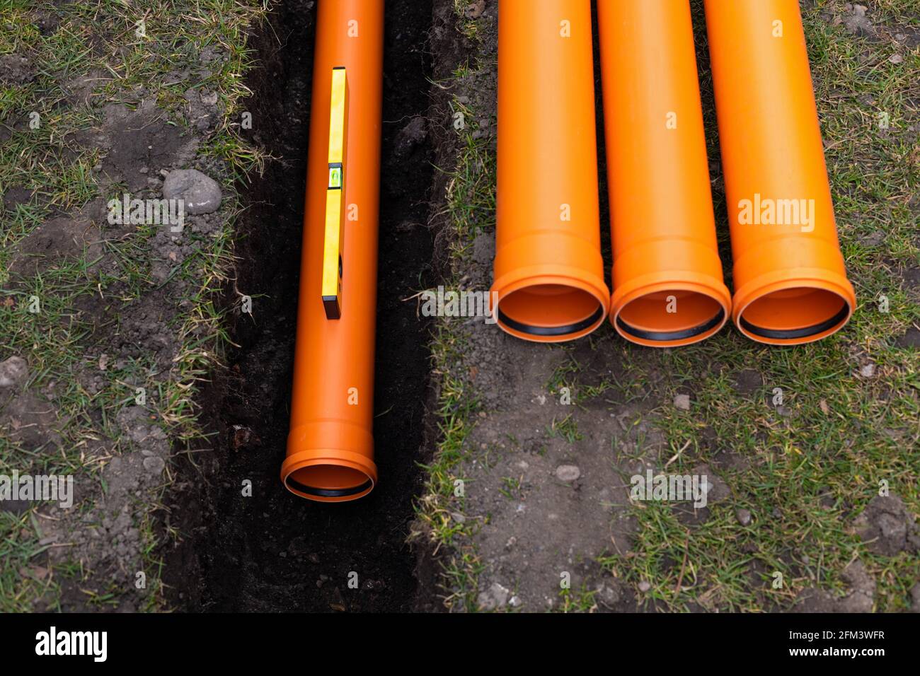 Laying down orange PVC drainage pipes into the ground Stock Photo - Alamy