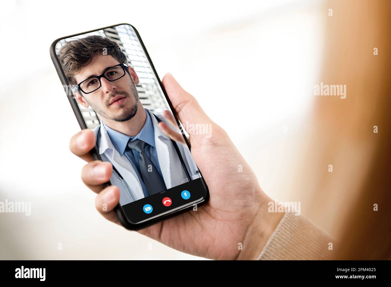 Patient making video call with doctor online via mobile phone, home ...