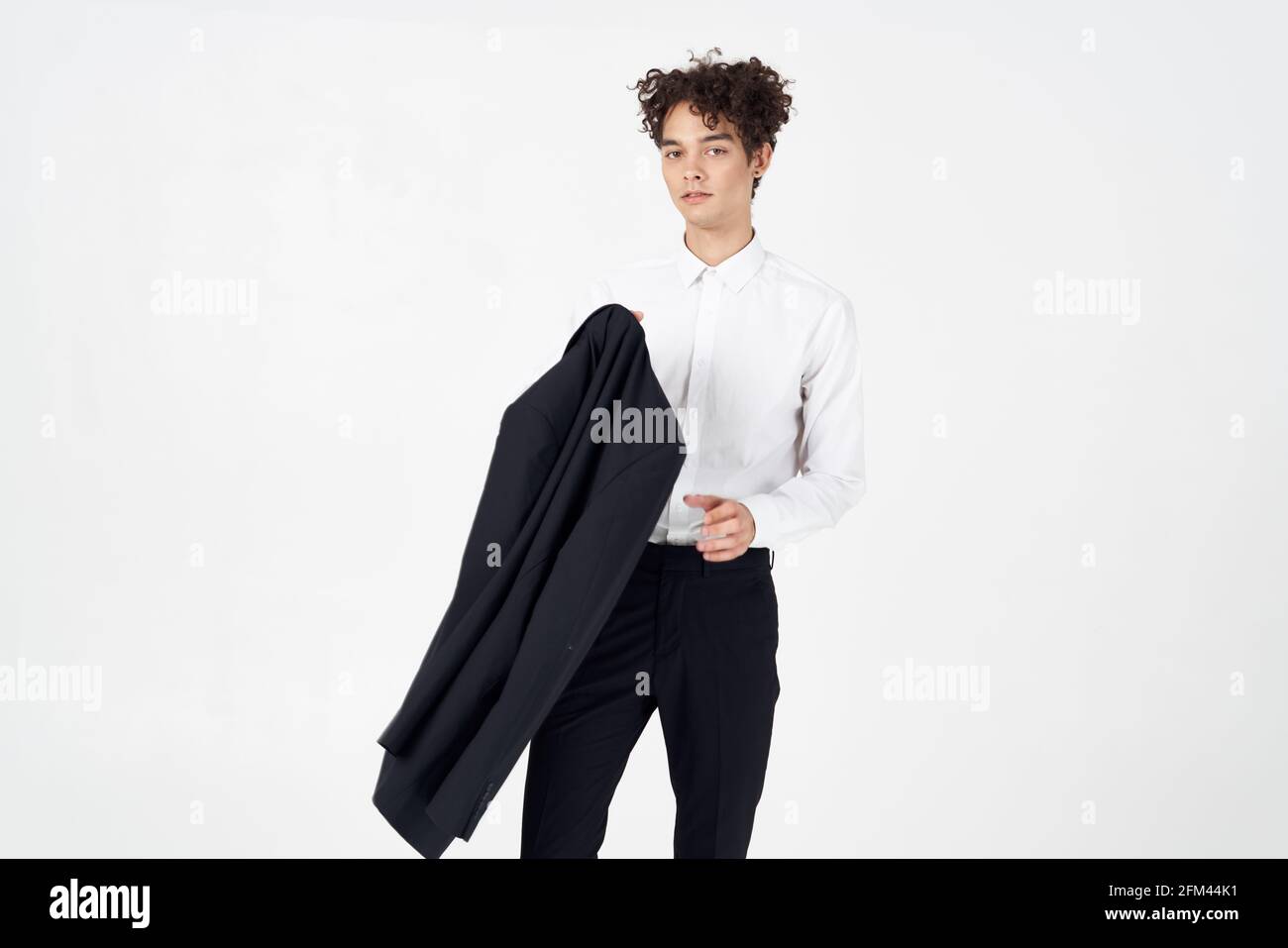 fashionable guy in a classic suit with a jacket in his hand on a light ...