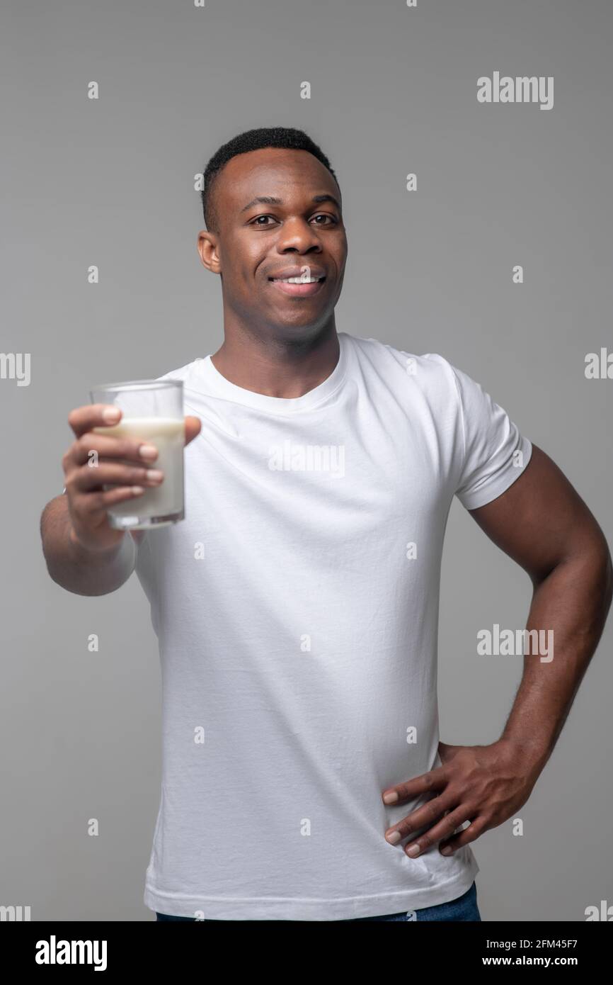 Cheerful man holding out glass of milk forward Stock Photo - Alamy
