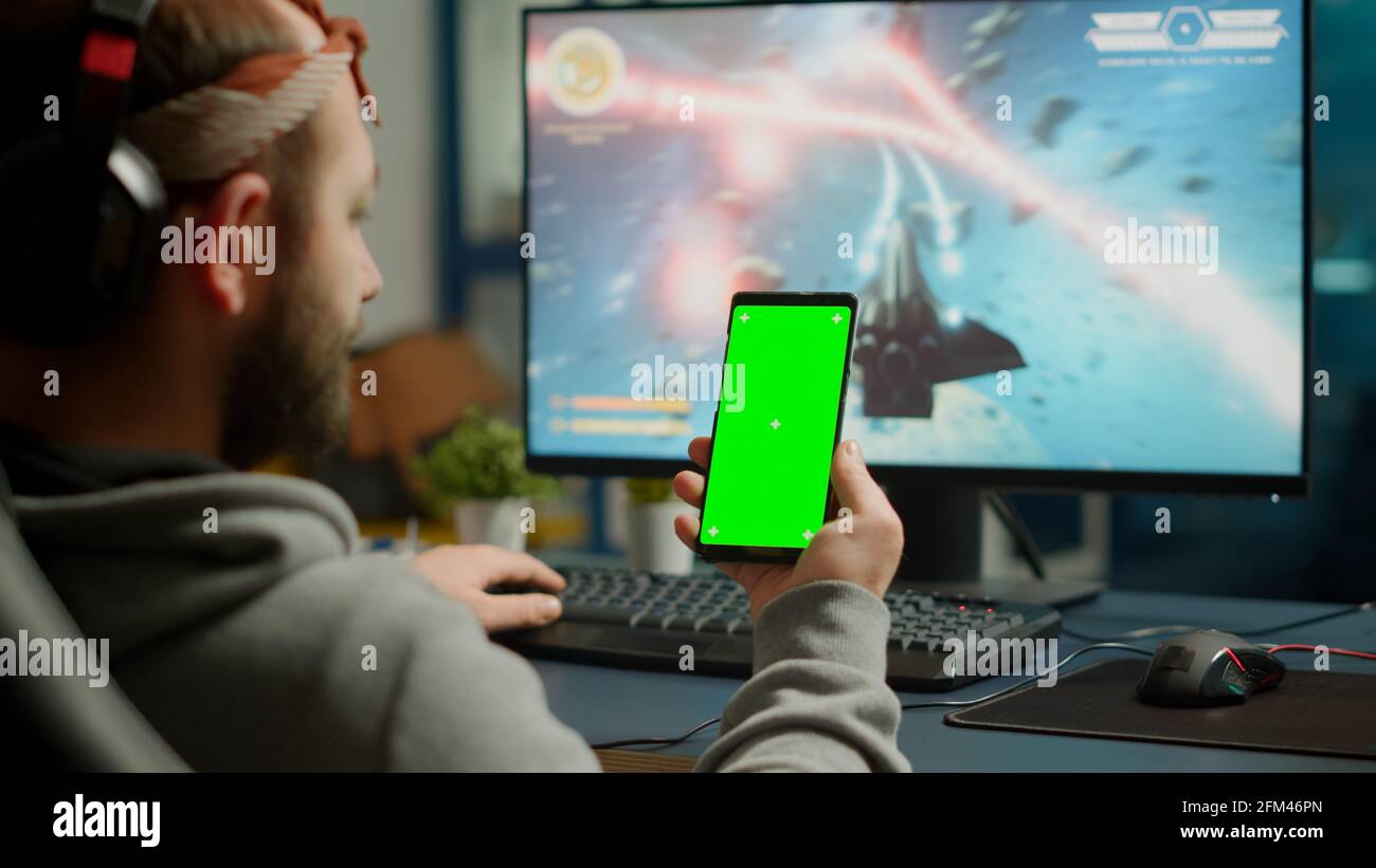 Concentrate gamer holding phone with green screen mock up chorma key ...