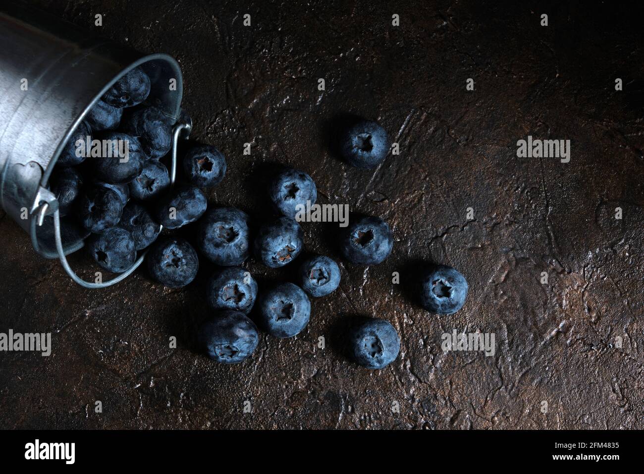 Blueberry berries spilled from metal bucket onto wooden table Stock ...