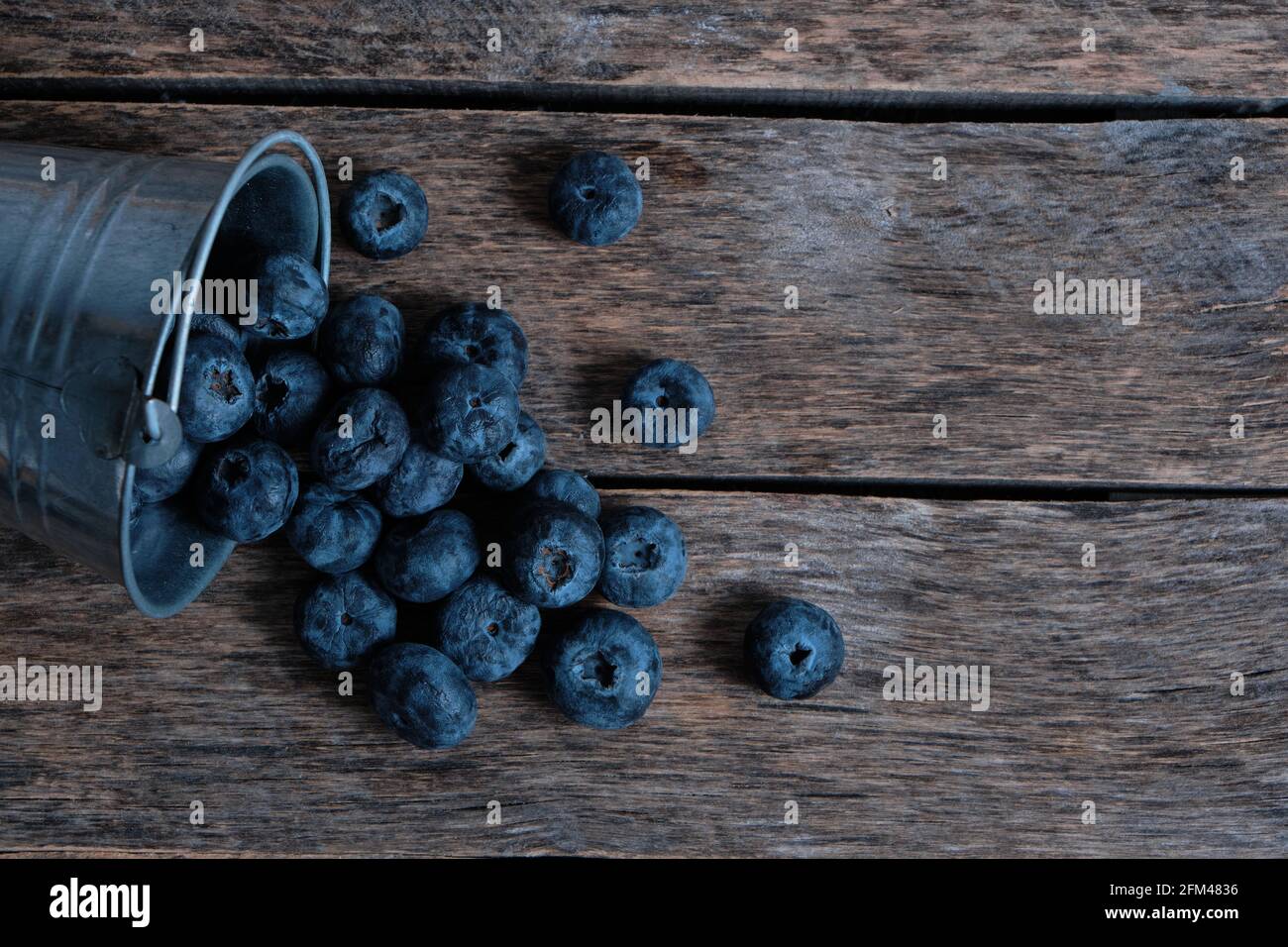 Blueberry berries spilled from metal bucket onto wooden table Stock ...