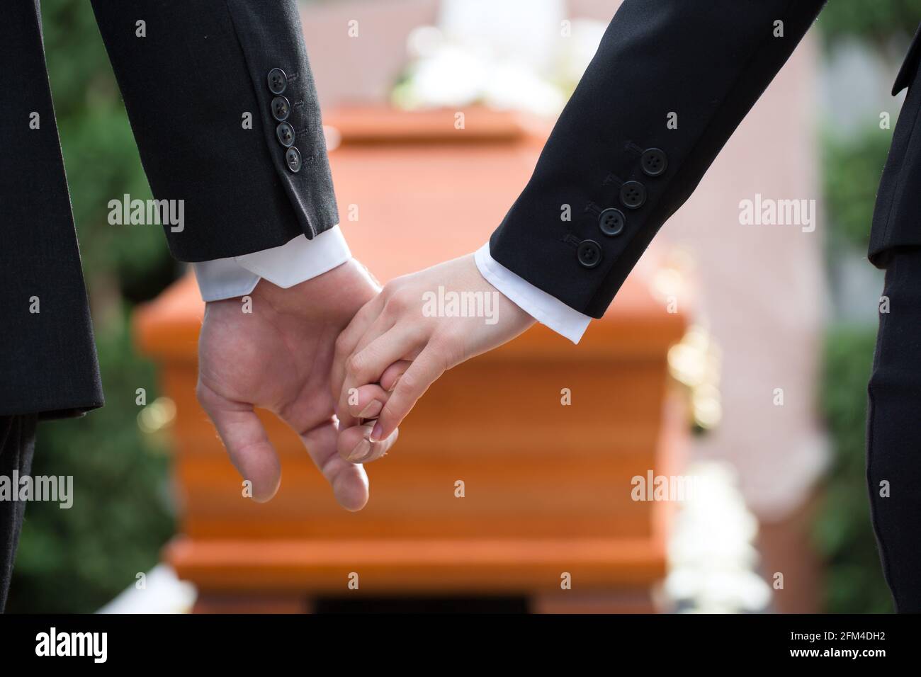 Religion, death and dolor - couple at funeral holding hands consoling ...