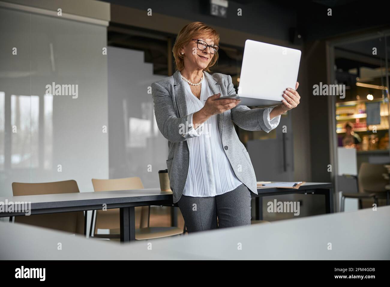 Pleasant office worker holding laptop in the air Stock Photo - Alamy