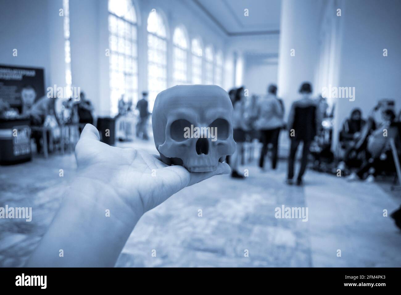 Skull printed on 3d printer in man's hand. On the back of a blurry plan ...
