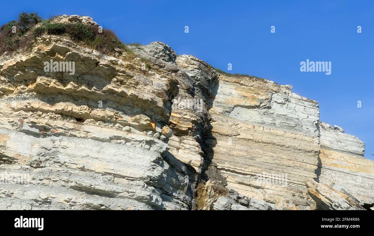 Low angle shot of a cliff with layers and a blue sky in the background ...