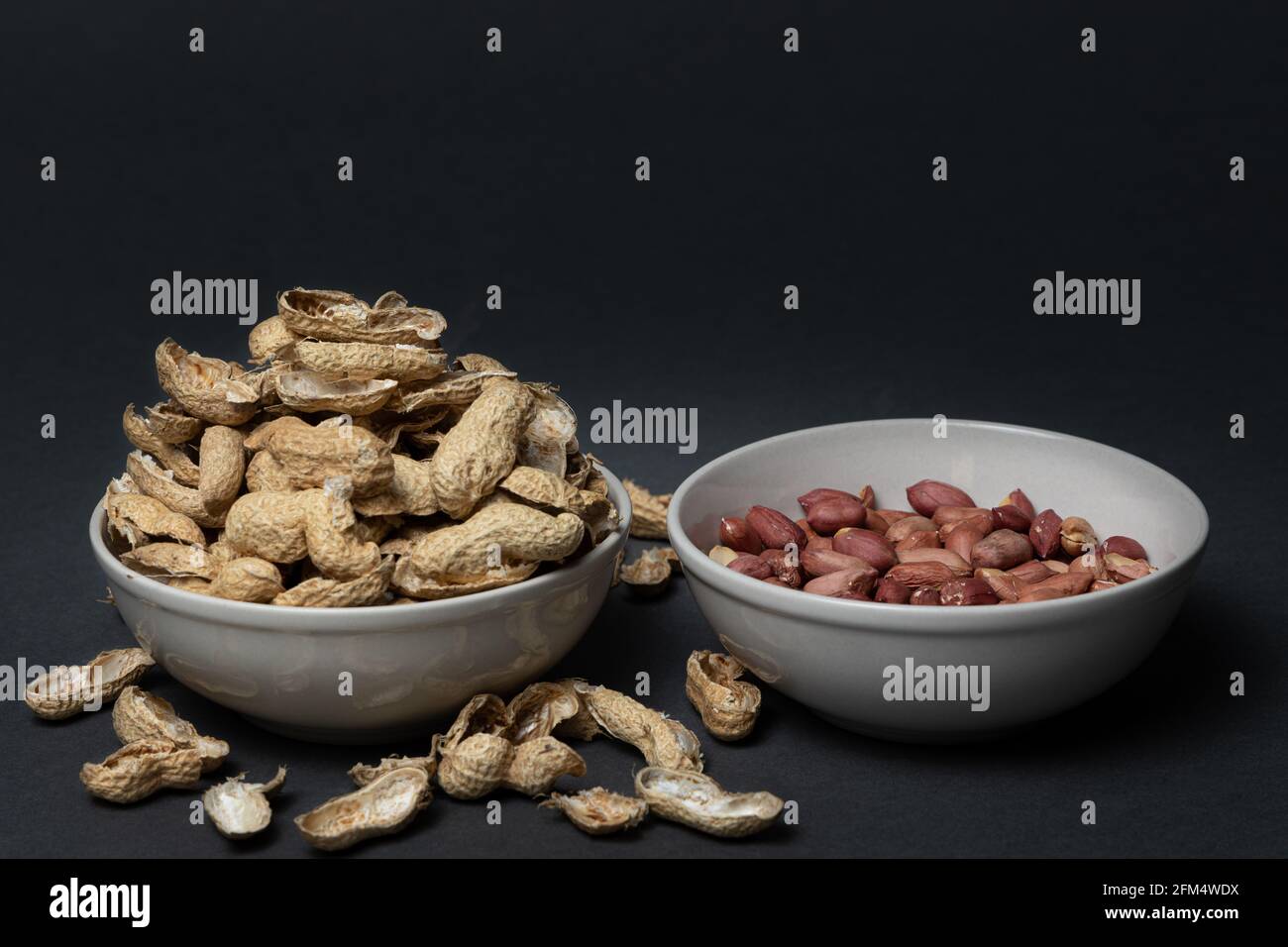 One bowl with peeled peanuts and another one full of peanut shells ...