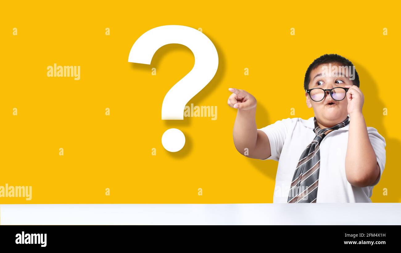 Asian boy pointing to big question mark on yellow background Stock ...