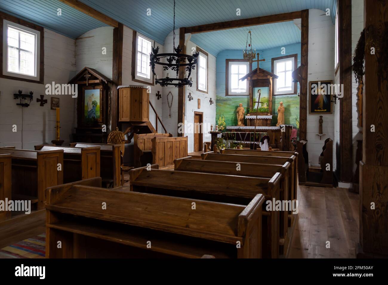 Interior of an old wood church. Blue ceilings, white walls, wooden pews ...