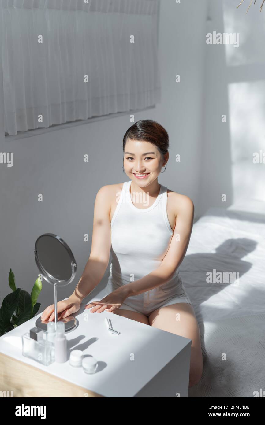 Portrait of beauty smiling asian woman applying lotion skin during her ...