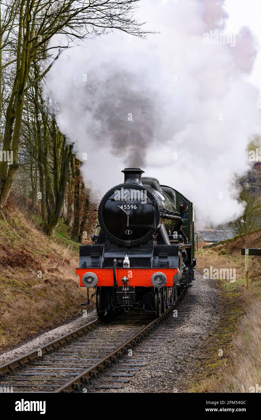 Historic steam train (loco) coming round bend in track, puffing smoke ...