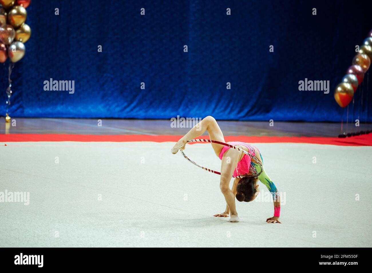 a gymnast girl performs with a hoop. flexible athlete performs a ...