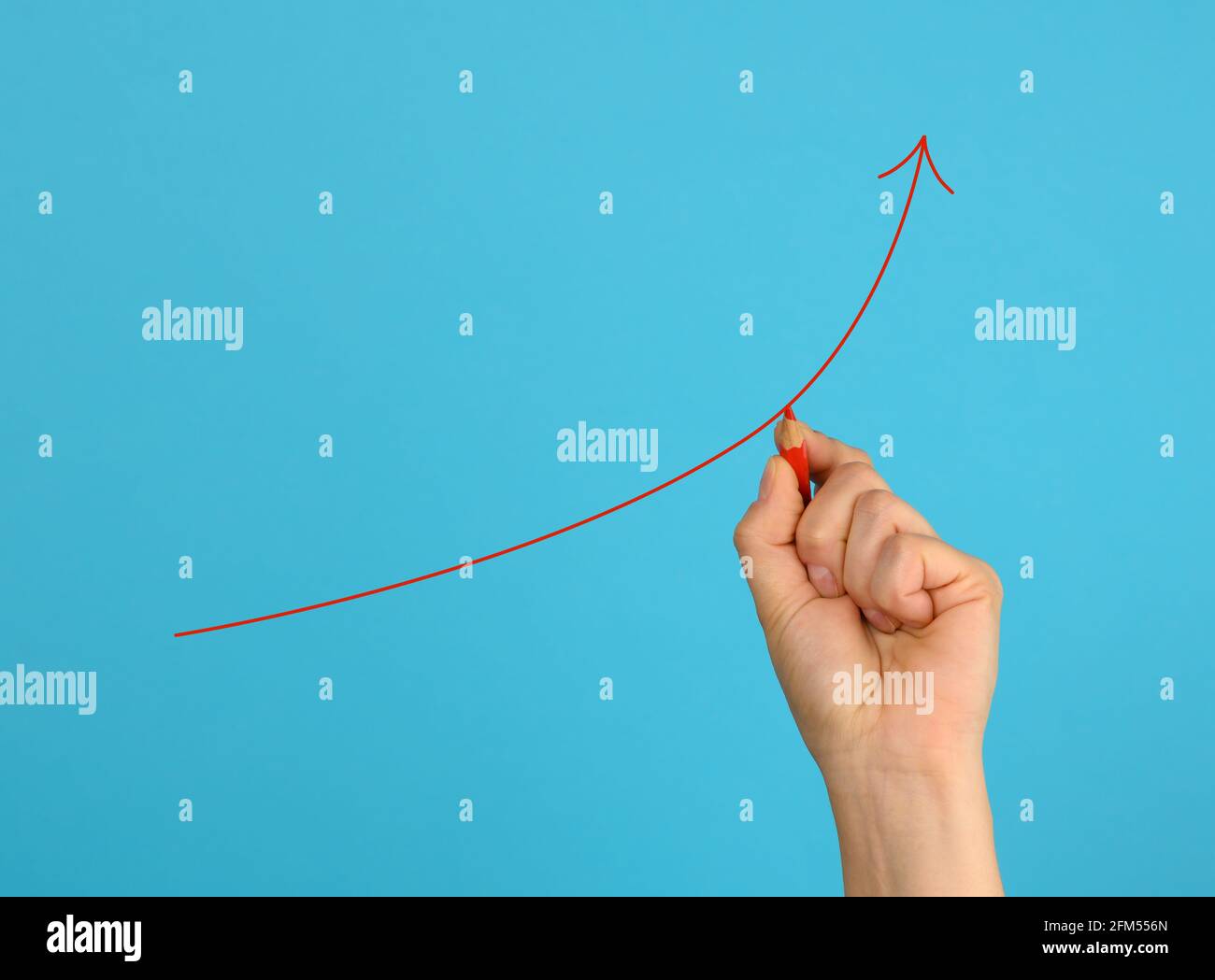 female hand draws a red up arrow on a blue background. The concept of ...