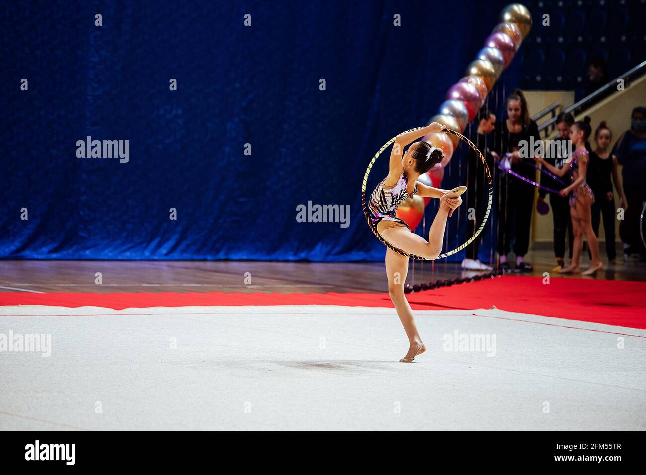 a gymnast girl performs with a hoop. flexible athlete performs a ...