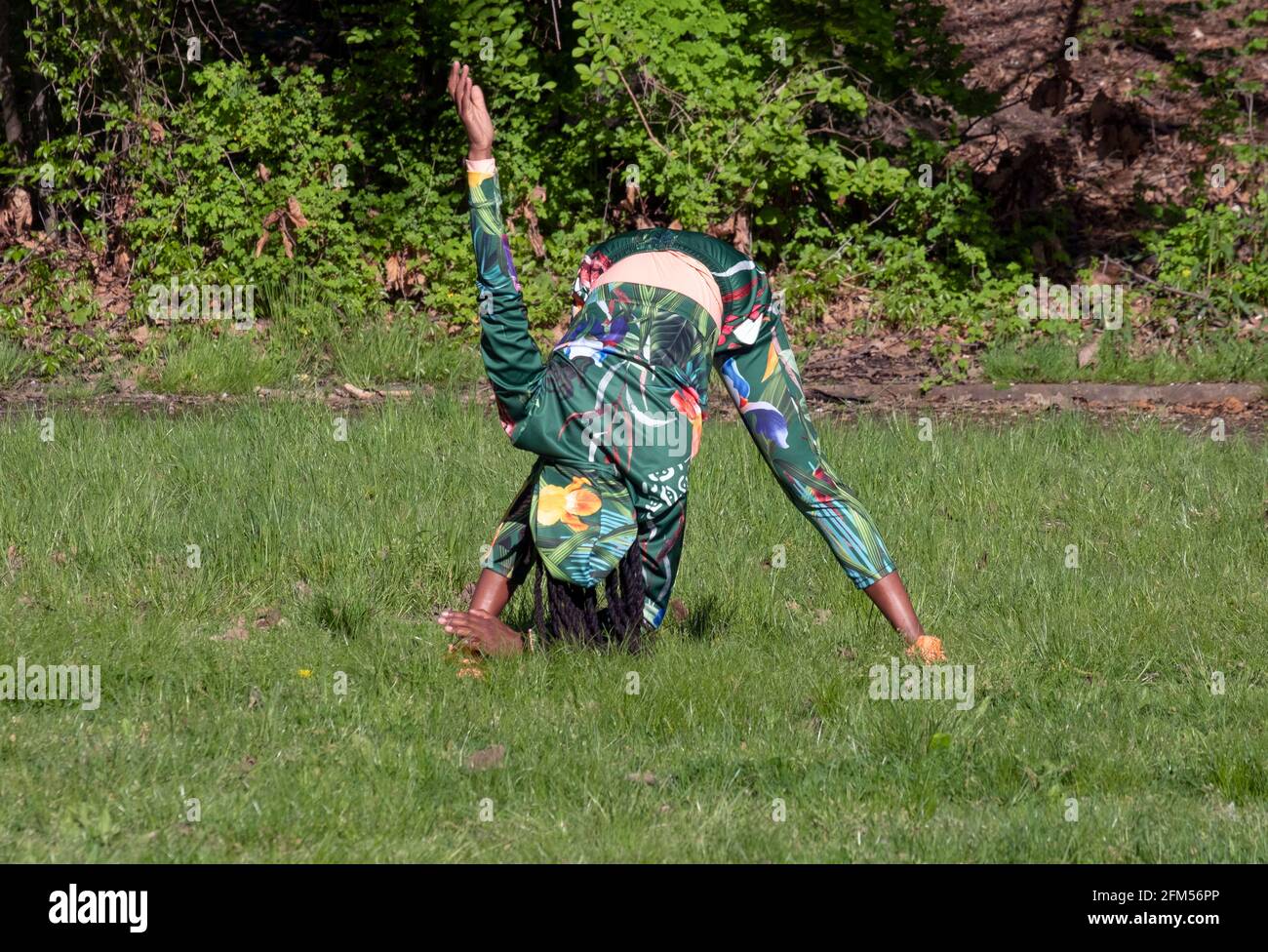 A fit nimble woman in her 50s at a meditative Yoga class in a park in ...