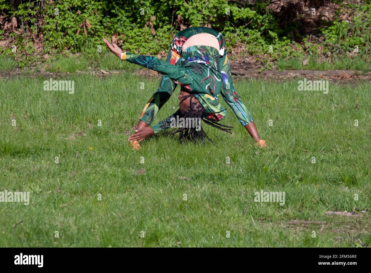 A fit nimble woman in her 50s at a meditative Yoga class in a park in ...