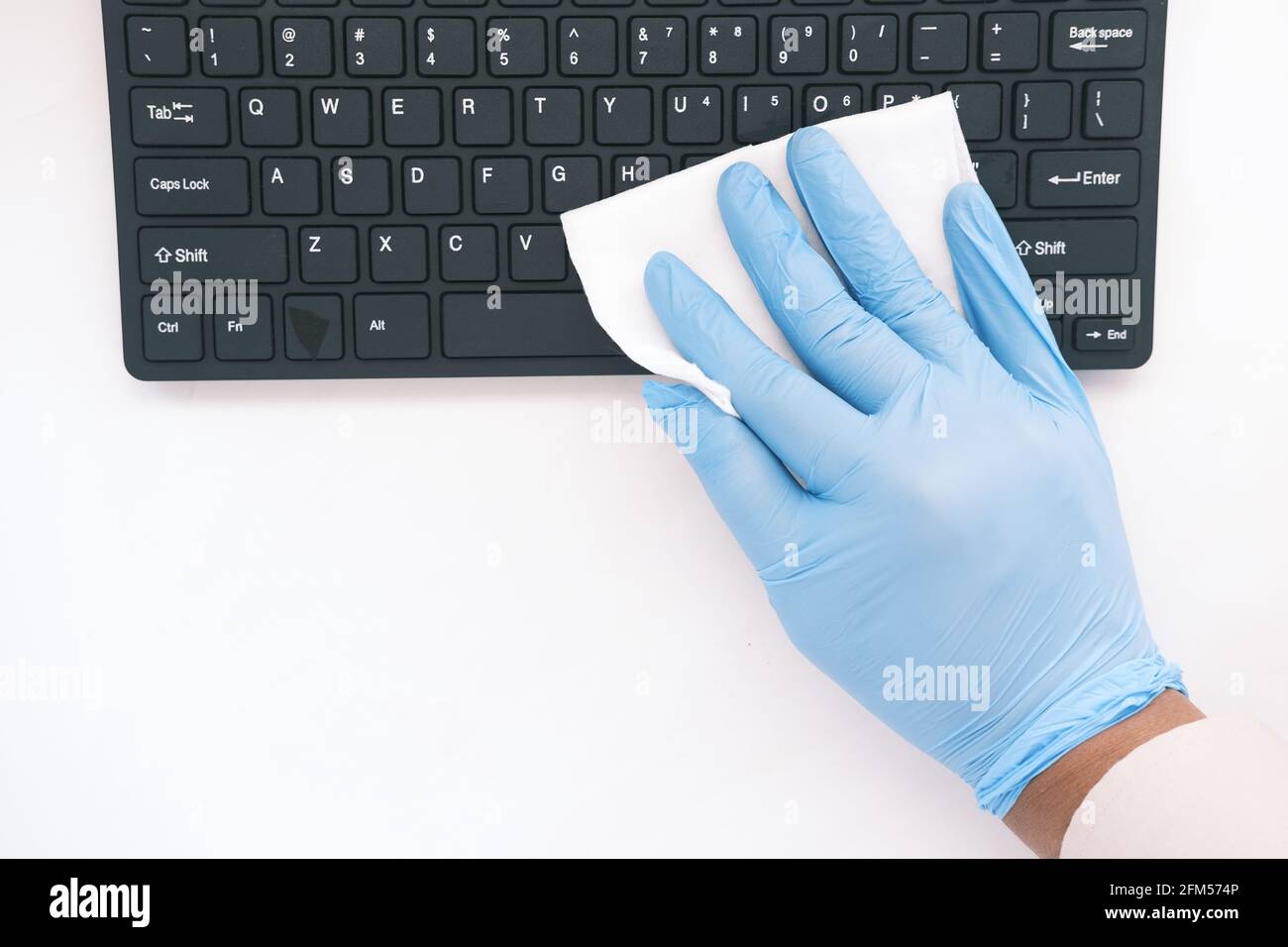 hand in blue rubber gloves and white tissue disinfecting keyboard Stock ...
