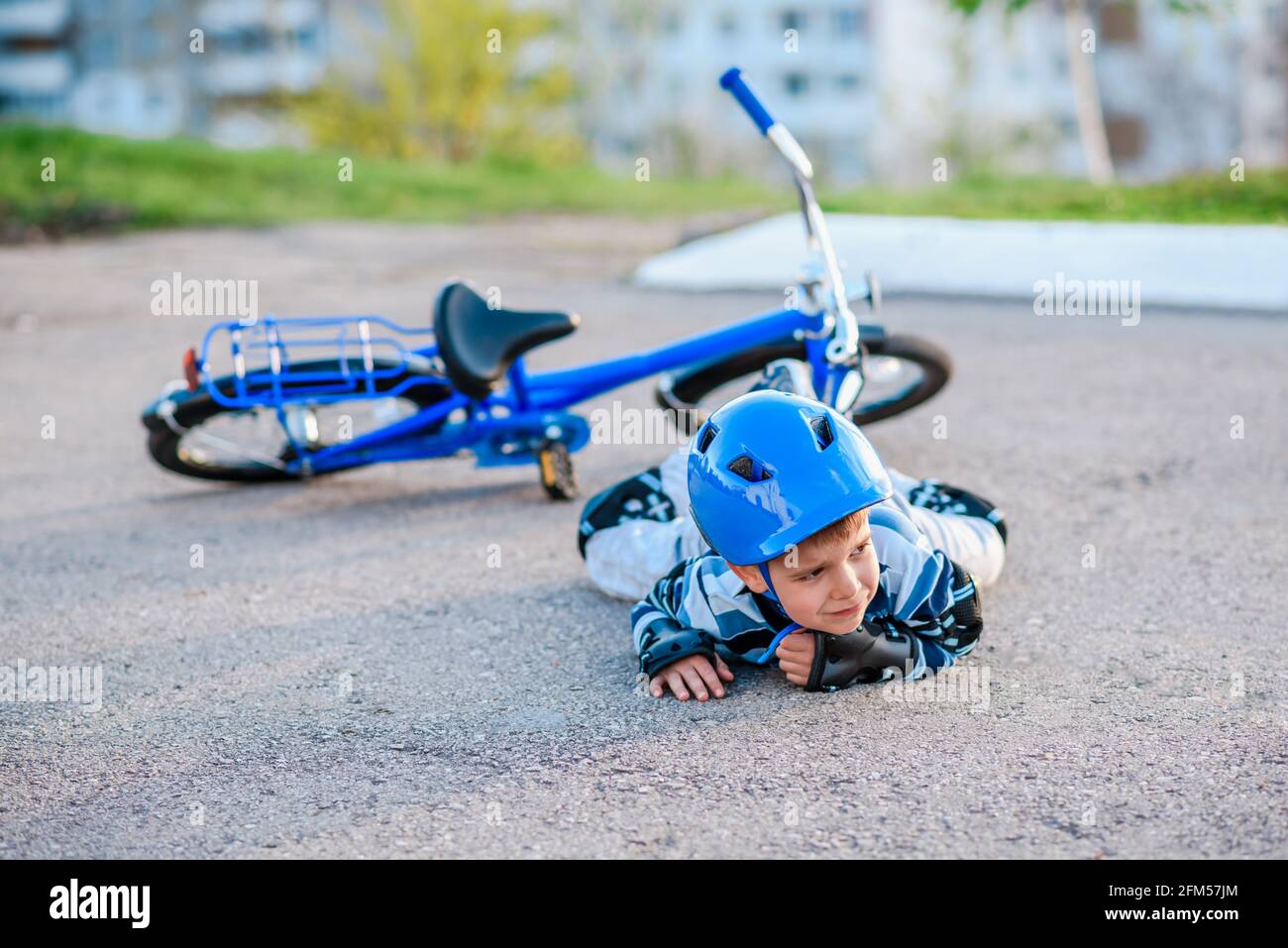 A small child in a helmet and protection fell from a bicycle onto the ...