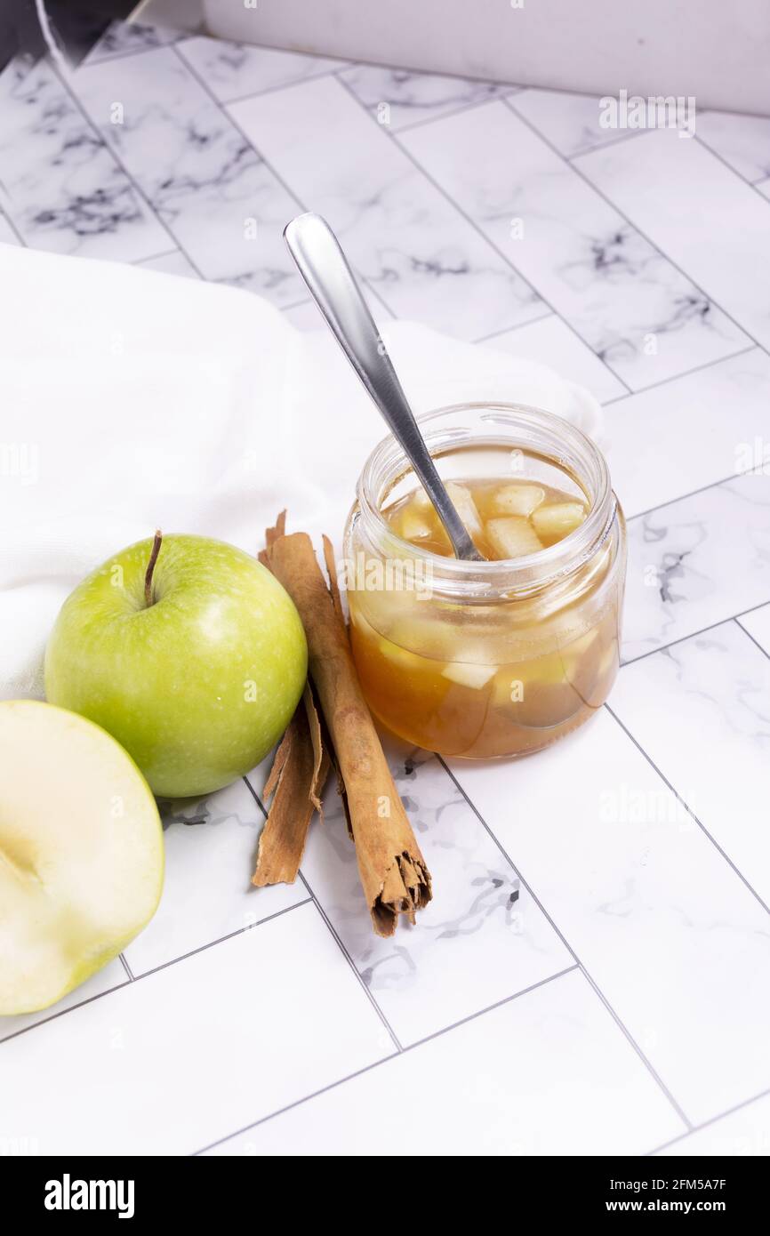 Green apples, cinnamon and a jar of apple jam on a white background ...