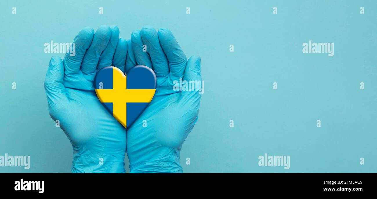 Doctors hands wearing surgical gloves holding Sweden flag heart Stock ...