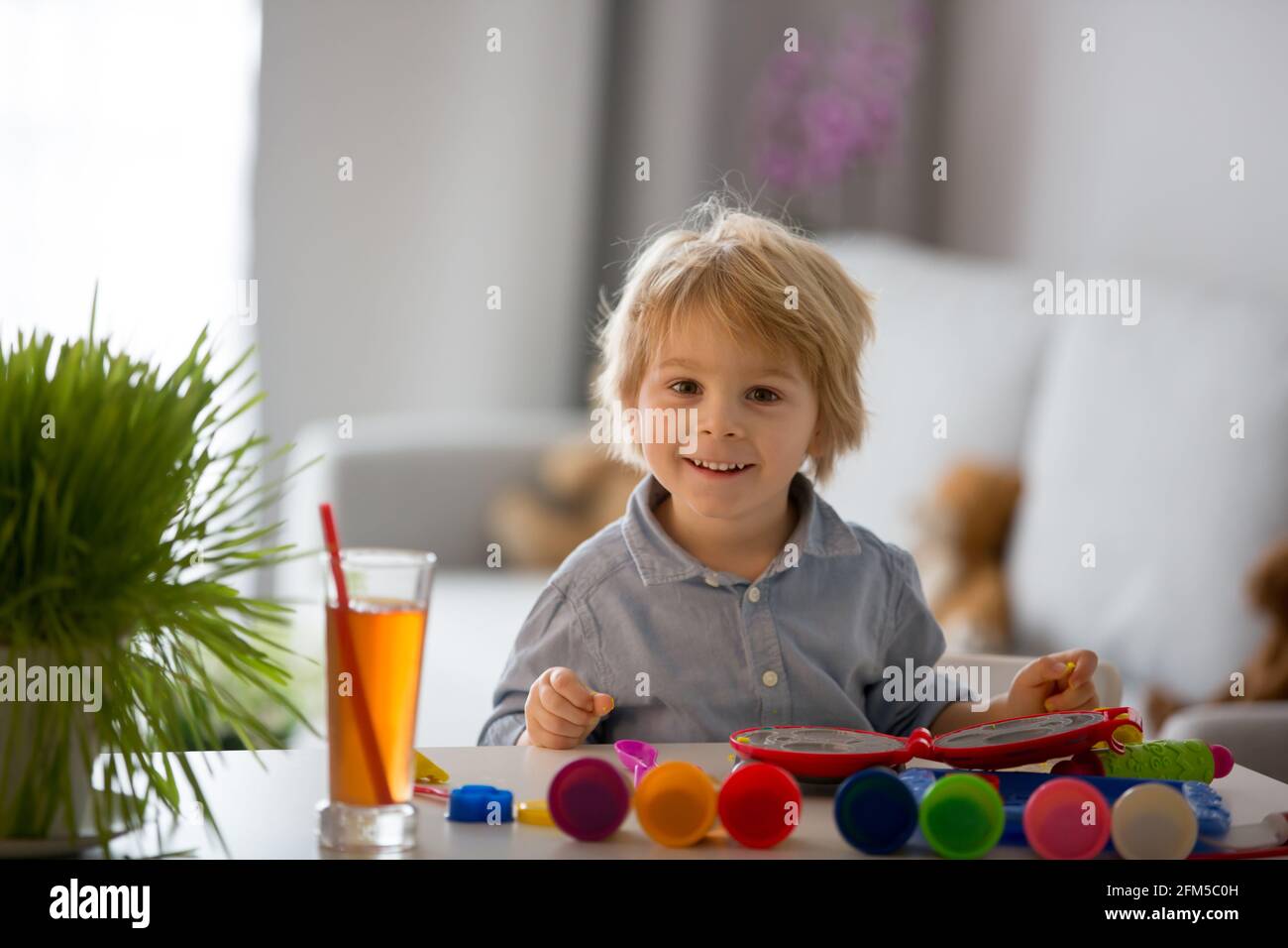 Cute blond child, sweet boy, playing with play doh modeline at home ...