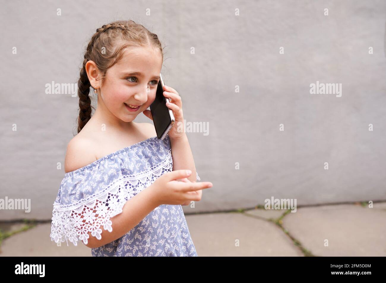 happy child, girl talking on cell, smart phone, outdoors. Positive ...