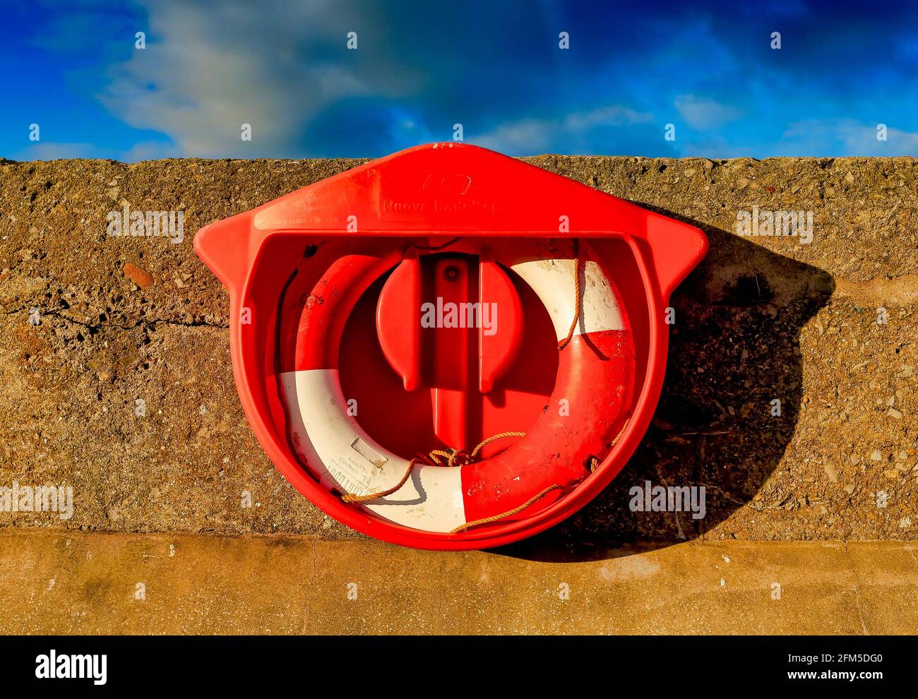 Red life preserver tied to the harbor wall Stock Photo - Alamy