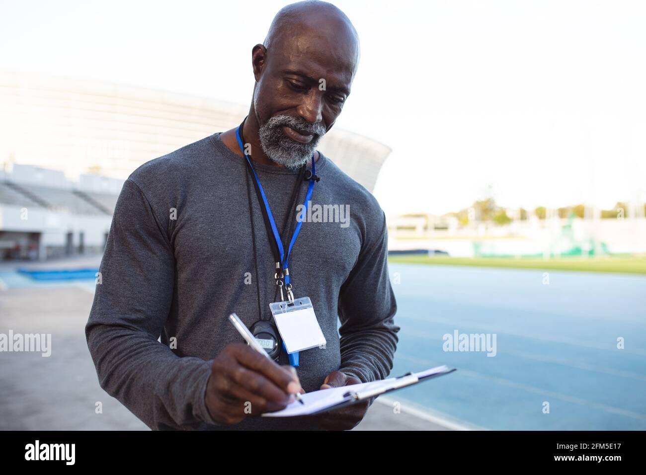 African american male coach with clipboard taking notes while standing ...