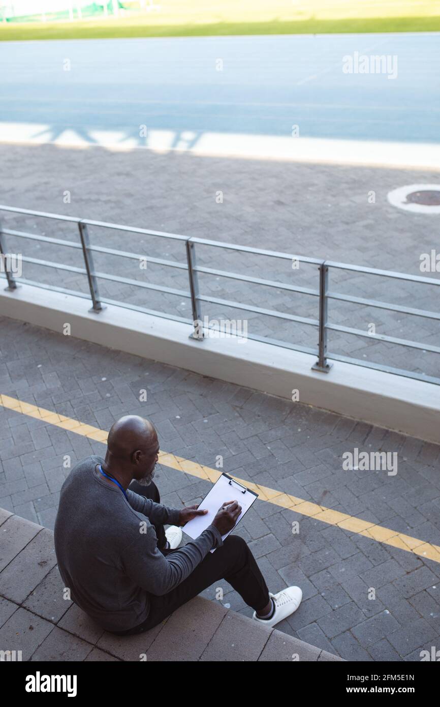 African american male coach with clipboard taking notes while sitting ...